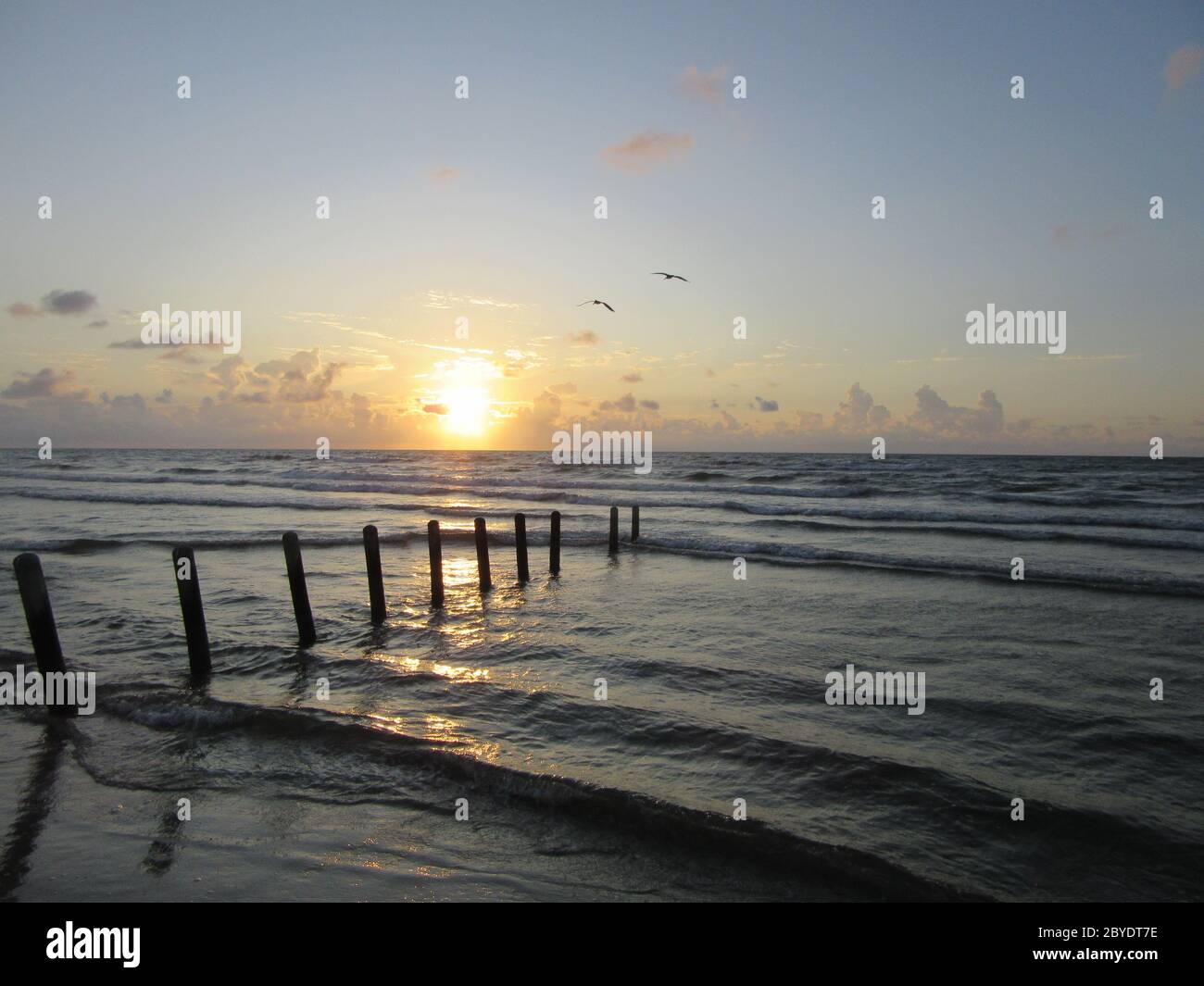 Sunrise is reflected in the water, on the sand, Packery Channel Jetty ...