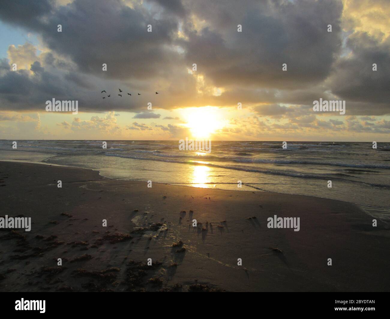 Sunrise is reflected in the water and sand on Packery Channel Jetty ...