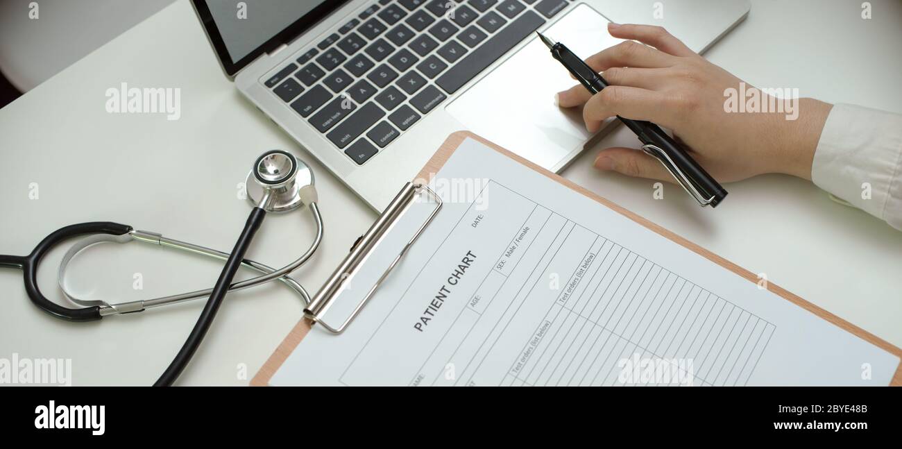 Close up view of doctor working with laptop, patient chart and ...