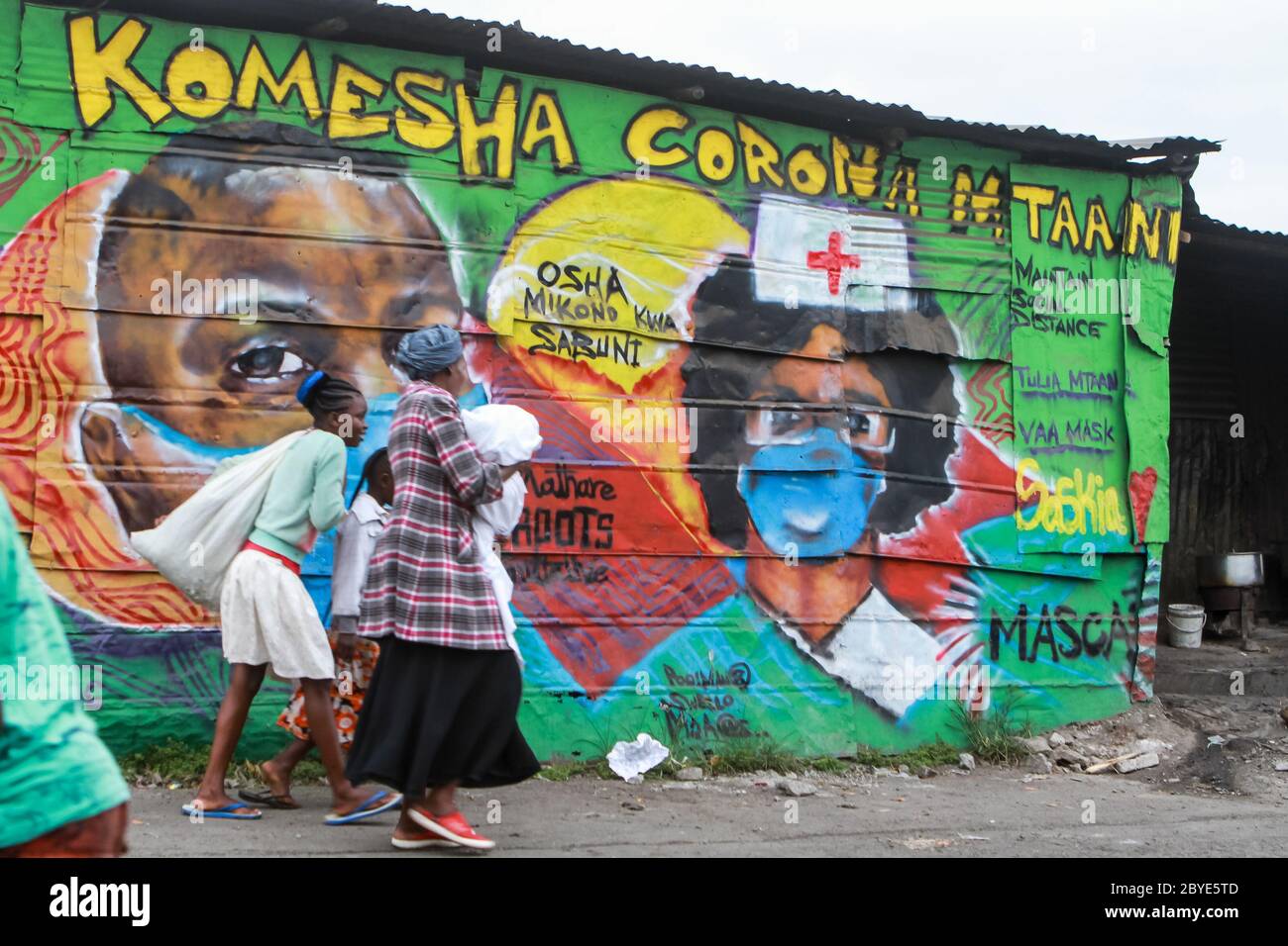 A mother and her children wearing face masks walk past a mural ...