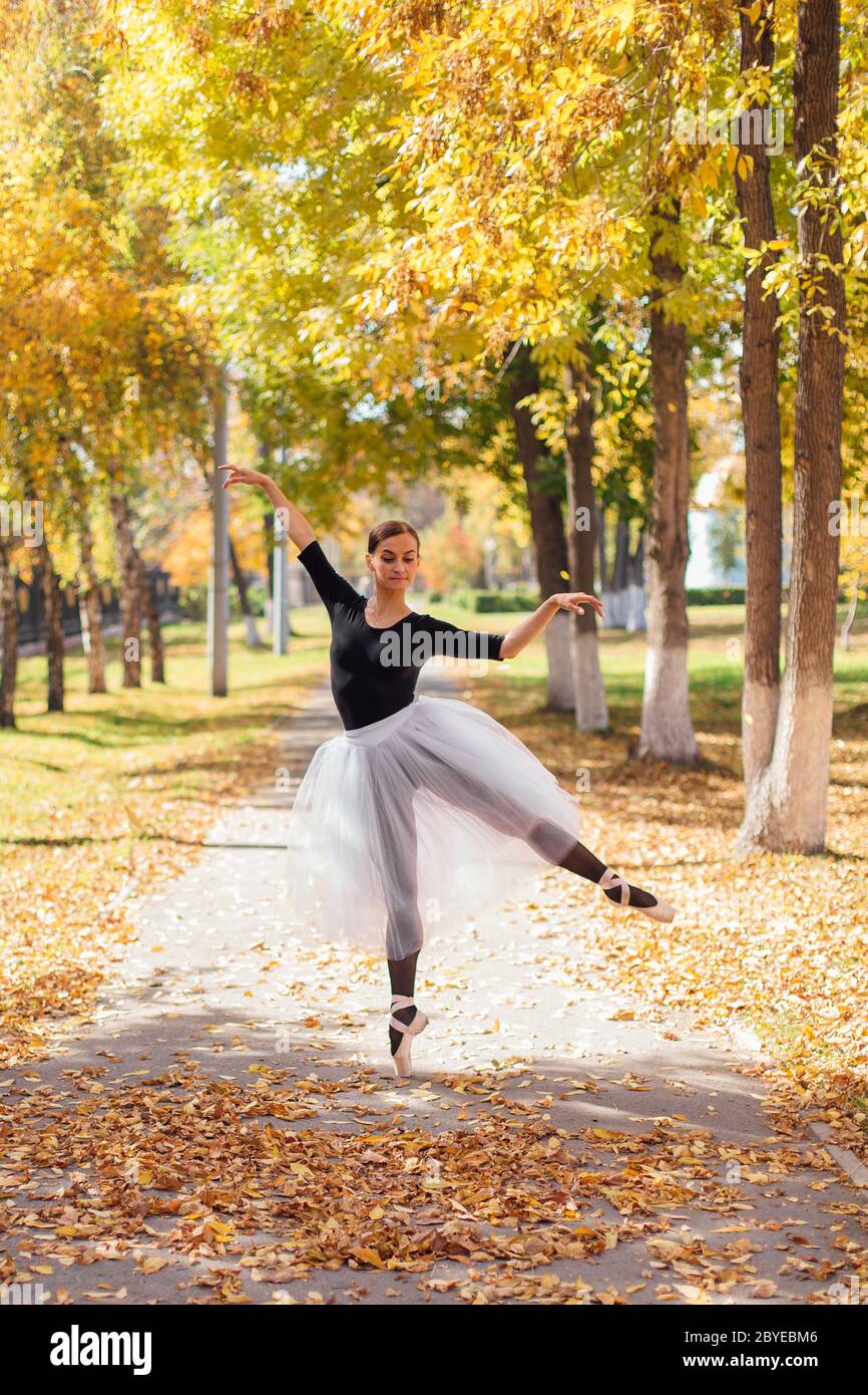 Woman ballerina in a white ballet skirt dancing in pointe shoes in a ...