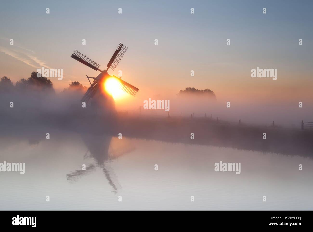 sun behind windmill and fog Stock Photo - Alamy