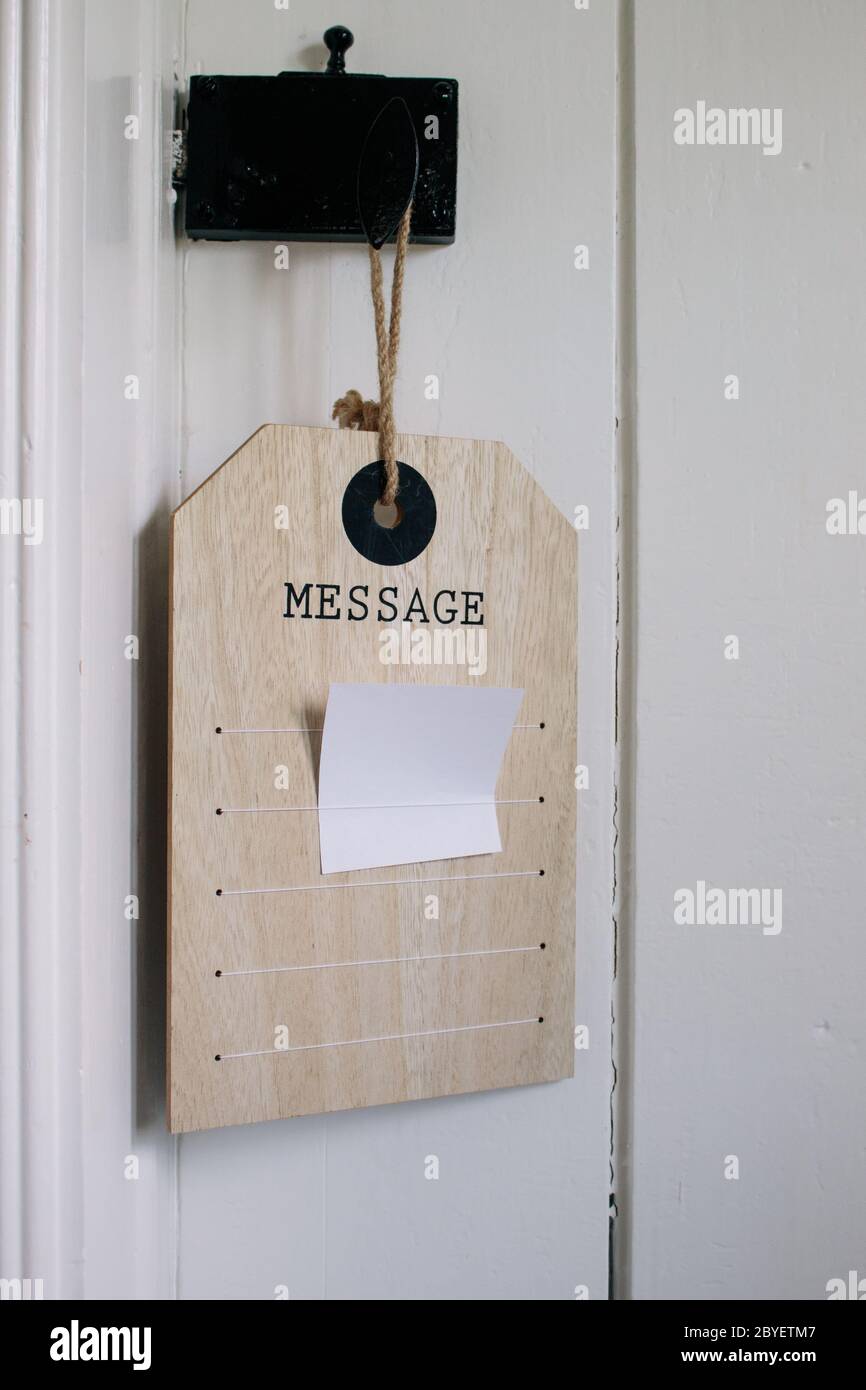 Wooden message board hanging on a white antique door, holding a white ...