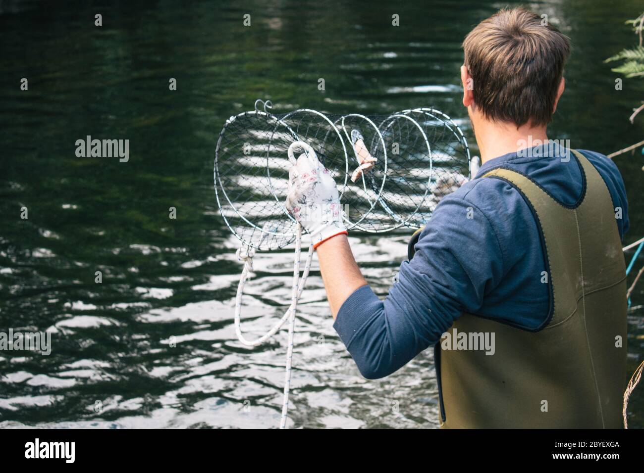 Young man throwing out a crab trap, fishing for crabs, summer in Sweden ...