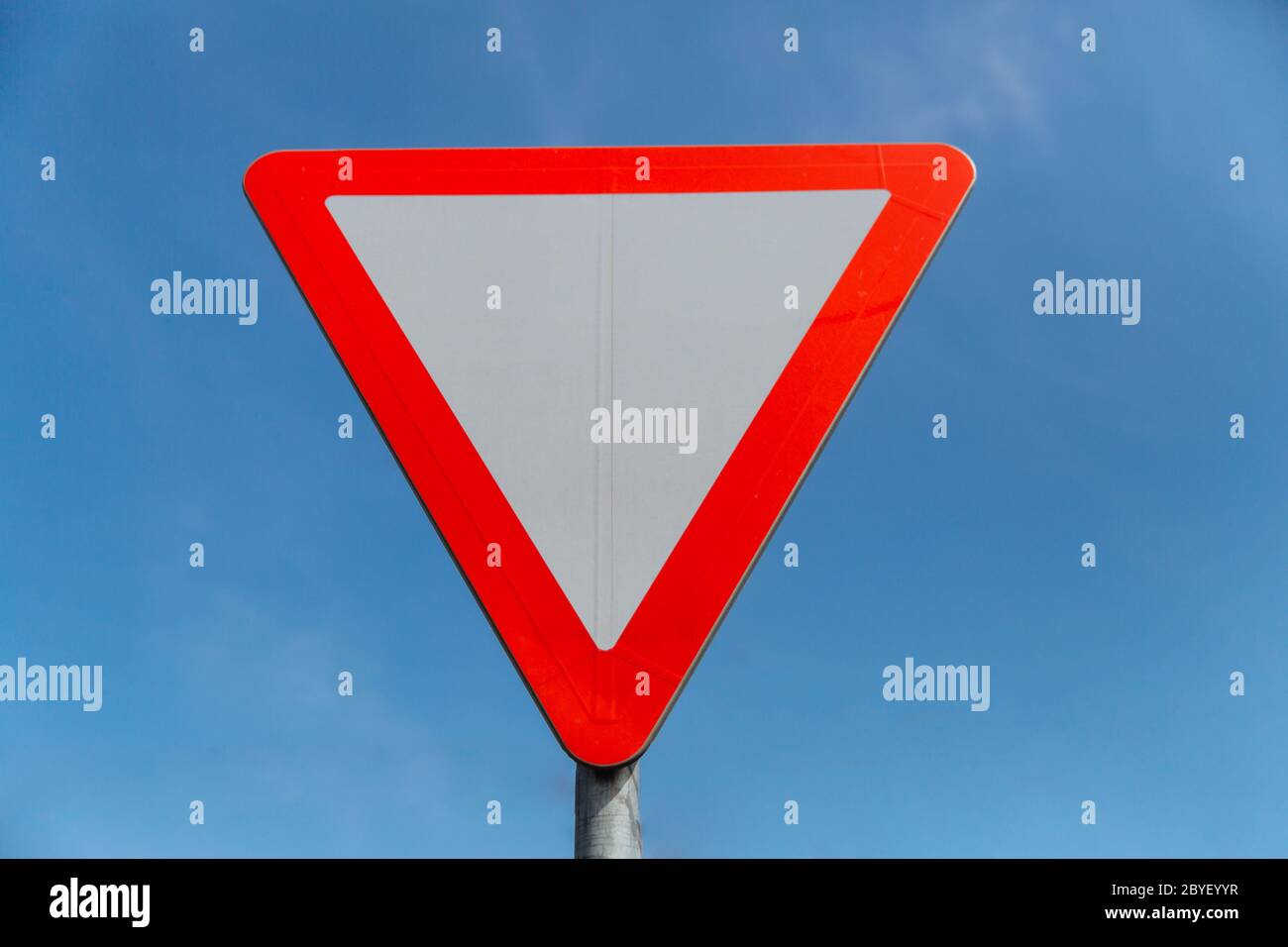 Road sign give way on blue sky background Stock Photo - Alamy
