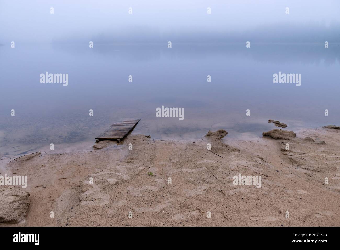 landscape with sandy beach after heavy rain, white fog on the lake ...
