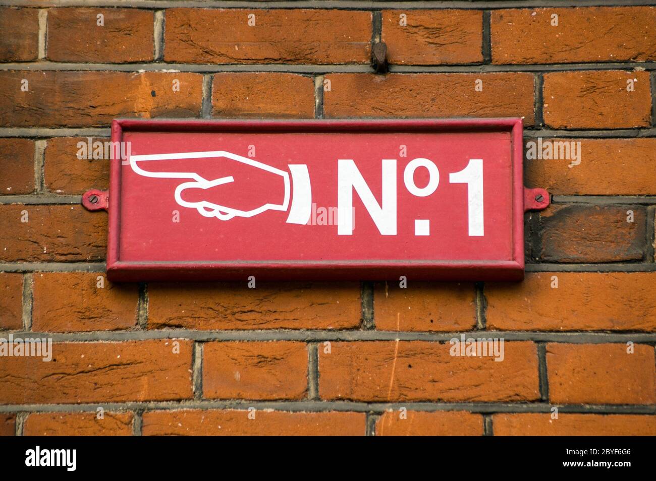 Historic hand painted sign on a brick wall pointing to house Number one ...