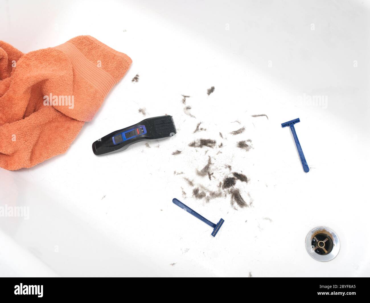 Razors, electric hair trimmer and cut hair on a bath bottom, indoor ...
