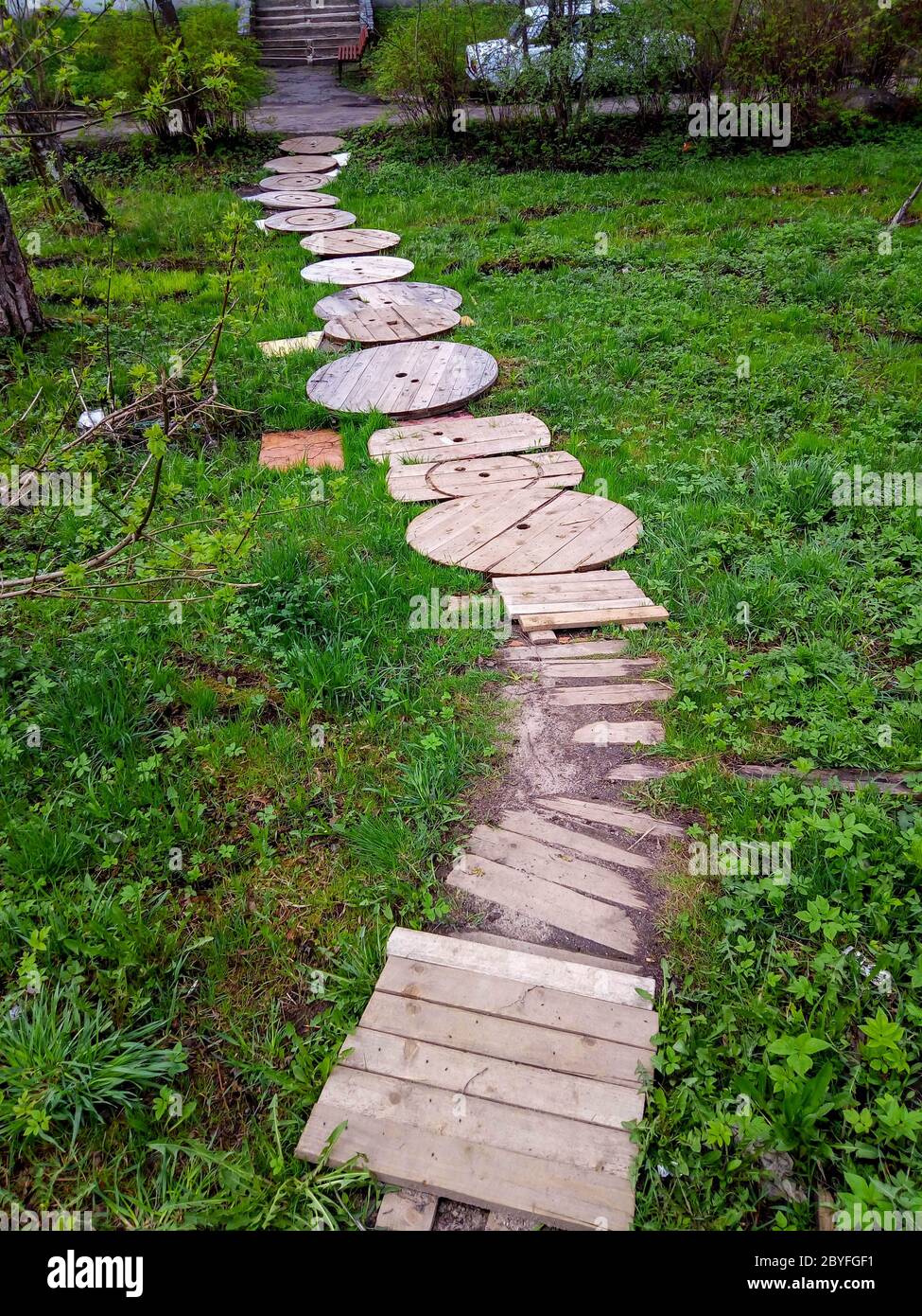 An elevated wooden path curves through a green lawn Stock Photo - Alamy