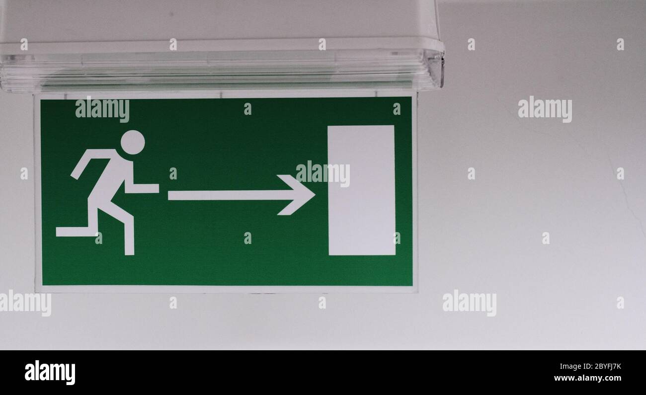 Emergency exit sign in a building glowing green Stock Photo - Alamy
