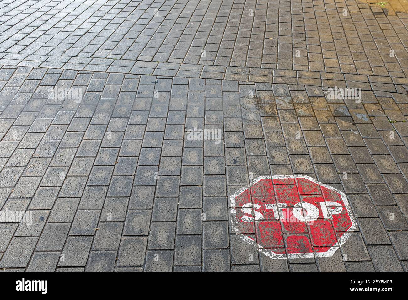 Stop signal painted on a cobble stone floor on an outdoor urban scene ...