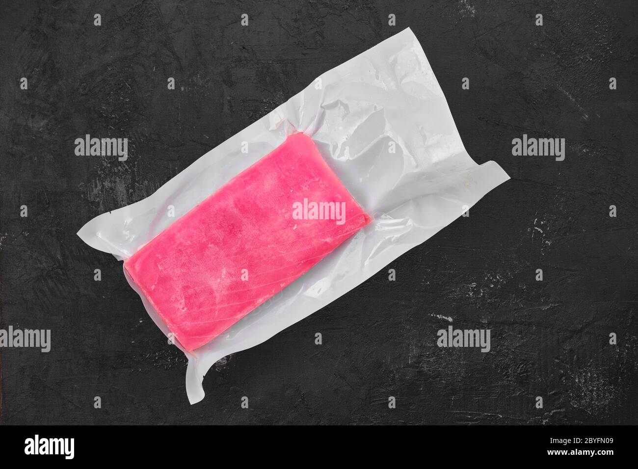 Raw frozen tuna fillet in vacuum packaging on black background Stock ...