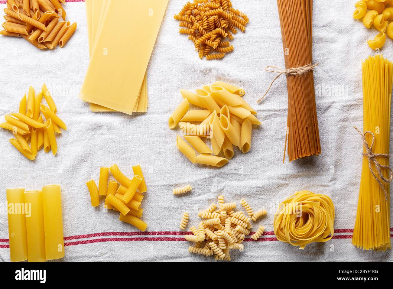 Variety of types and shapes of Italian pasta top view on white linen ...