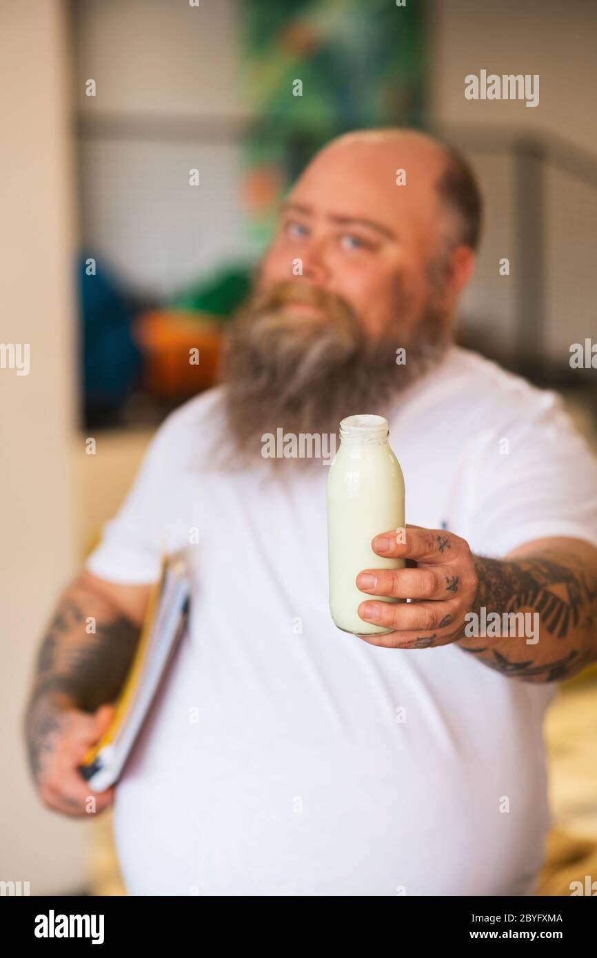 Bald bearded plump man holding a bottle with milk Stock Photo - Alamy