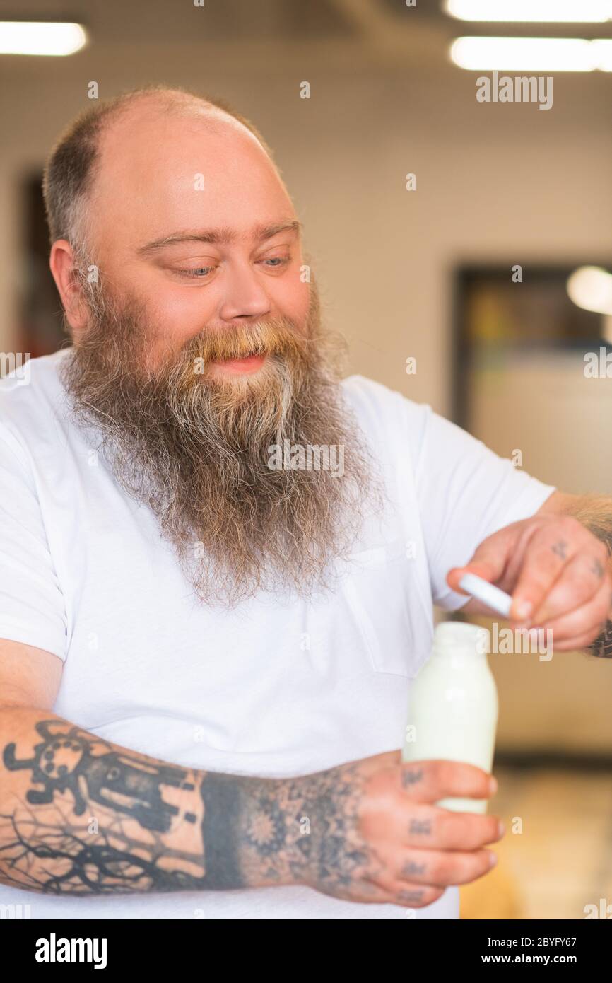 Bald bearded plump man opening a bottle with milk Stock Photo - Alamy