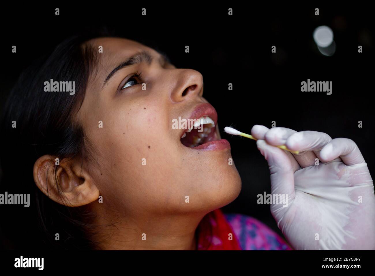 Doctor's hand taking Saliva test from young woman's mouth with Cotton ...