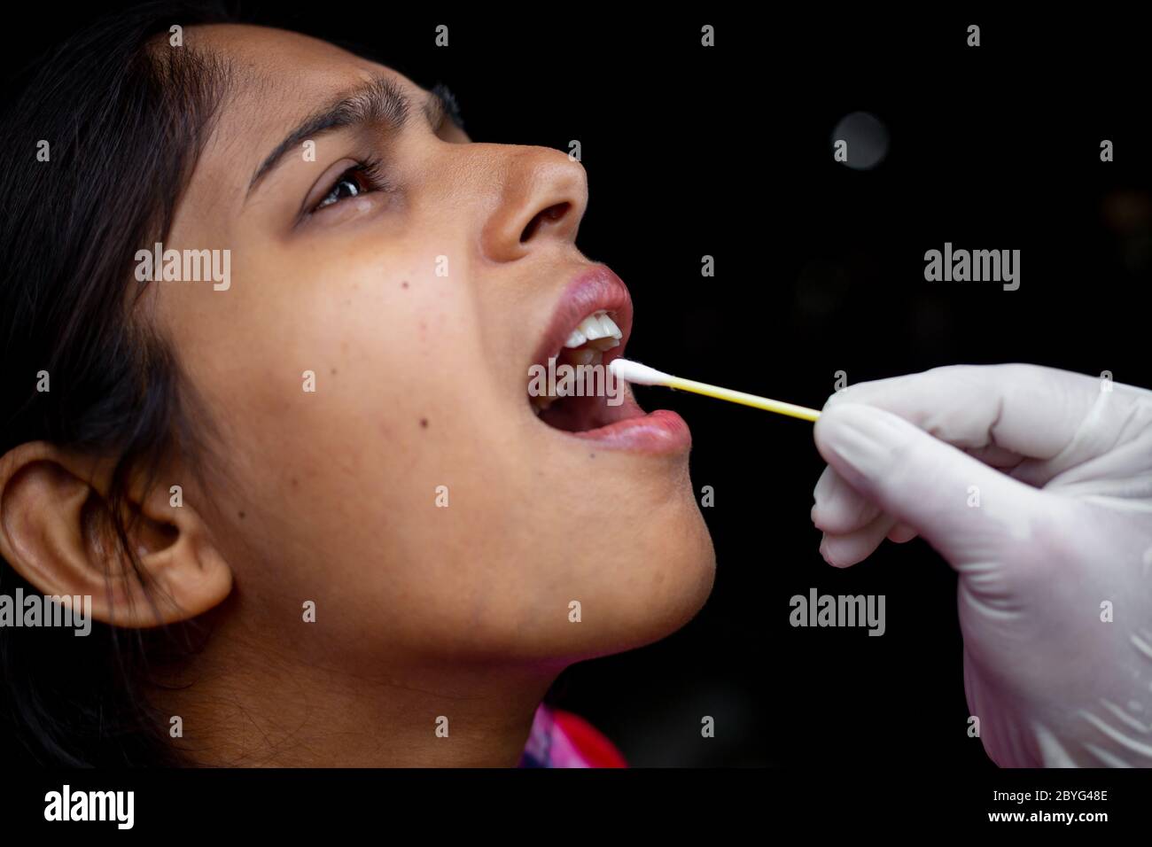 Doctor's hand taking Saliva test from young woman's mouth with Cotton ...