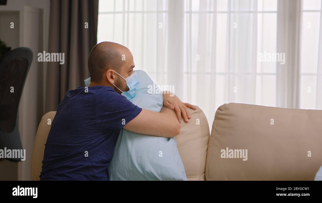 Man infected with covid-19 wearing a mask and hugging a pillow during ...