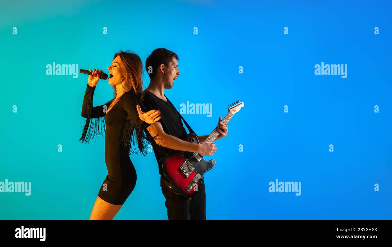 Caucasian musicians, singer and guitarist, isolated on blue studio ...
