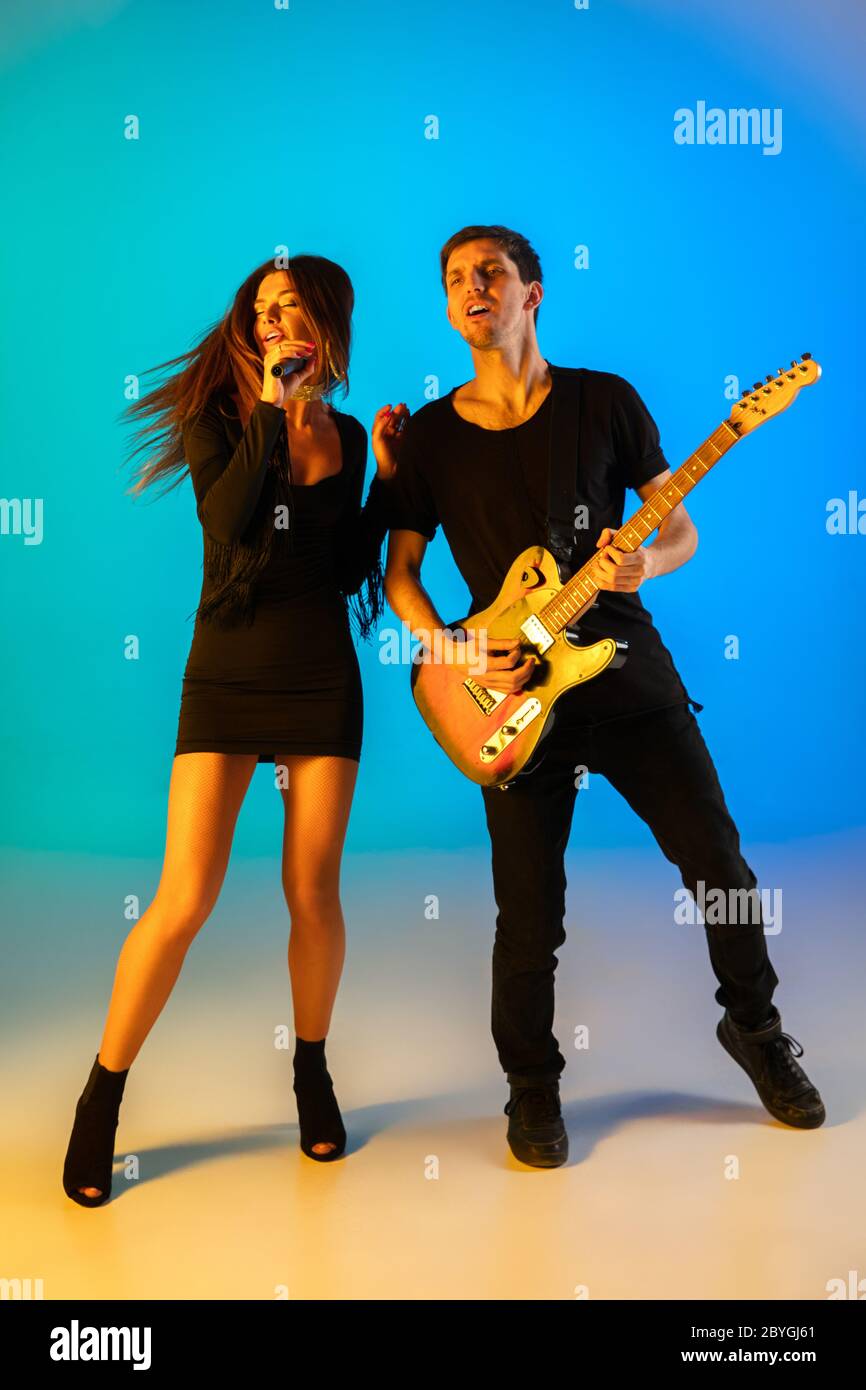 Caucasian musicians, singer and guitarist, isolated on blue studio ...