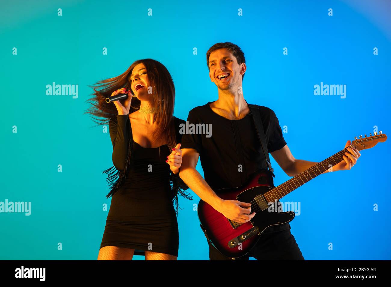 Caucasian musicians, singer and guitarist, isolated on blue studio ...