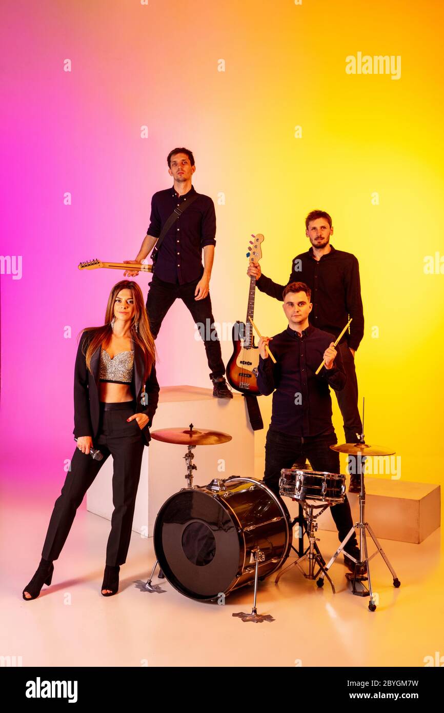 Young and joyful caucasian musicians performing on gradient studio ...
