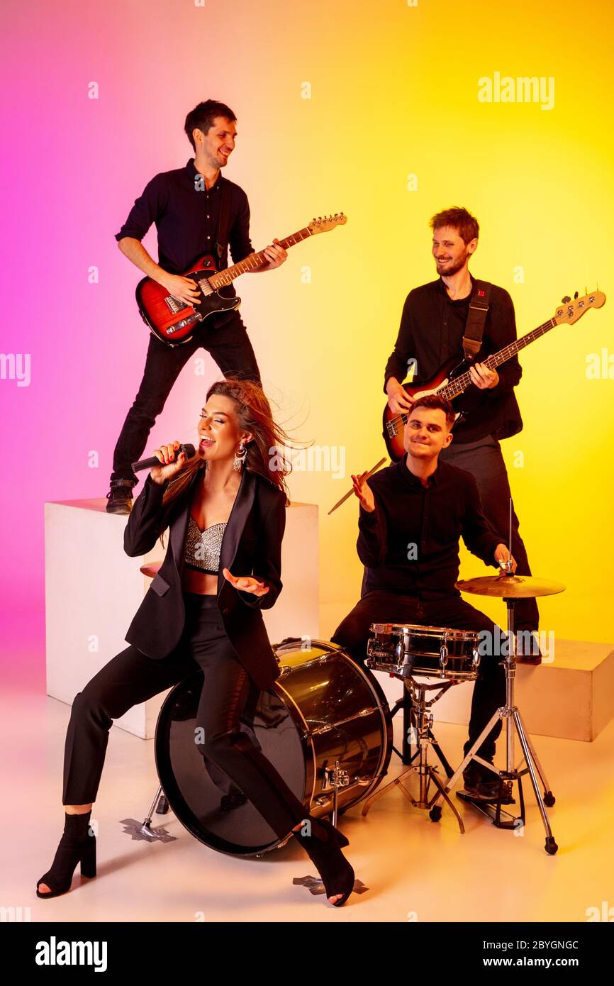 Young and joyful caucasian musicians performing on gradient studio ...