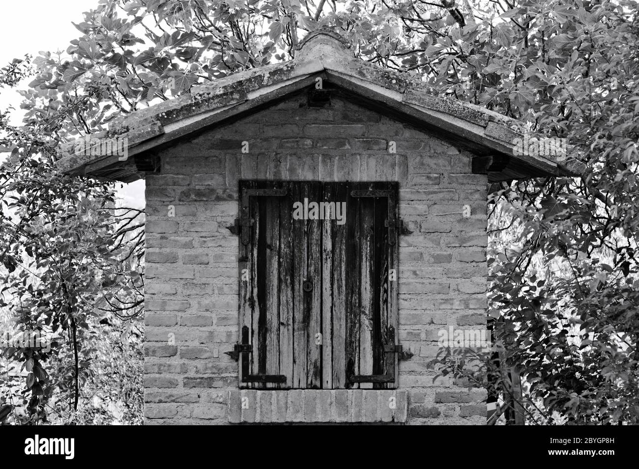 Facade of a little hut with a wooden shutter and tiles on the roof ...