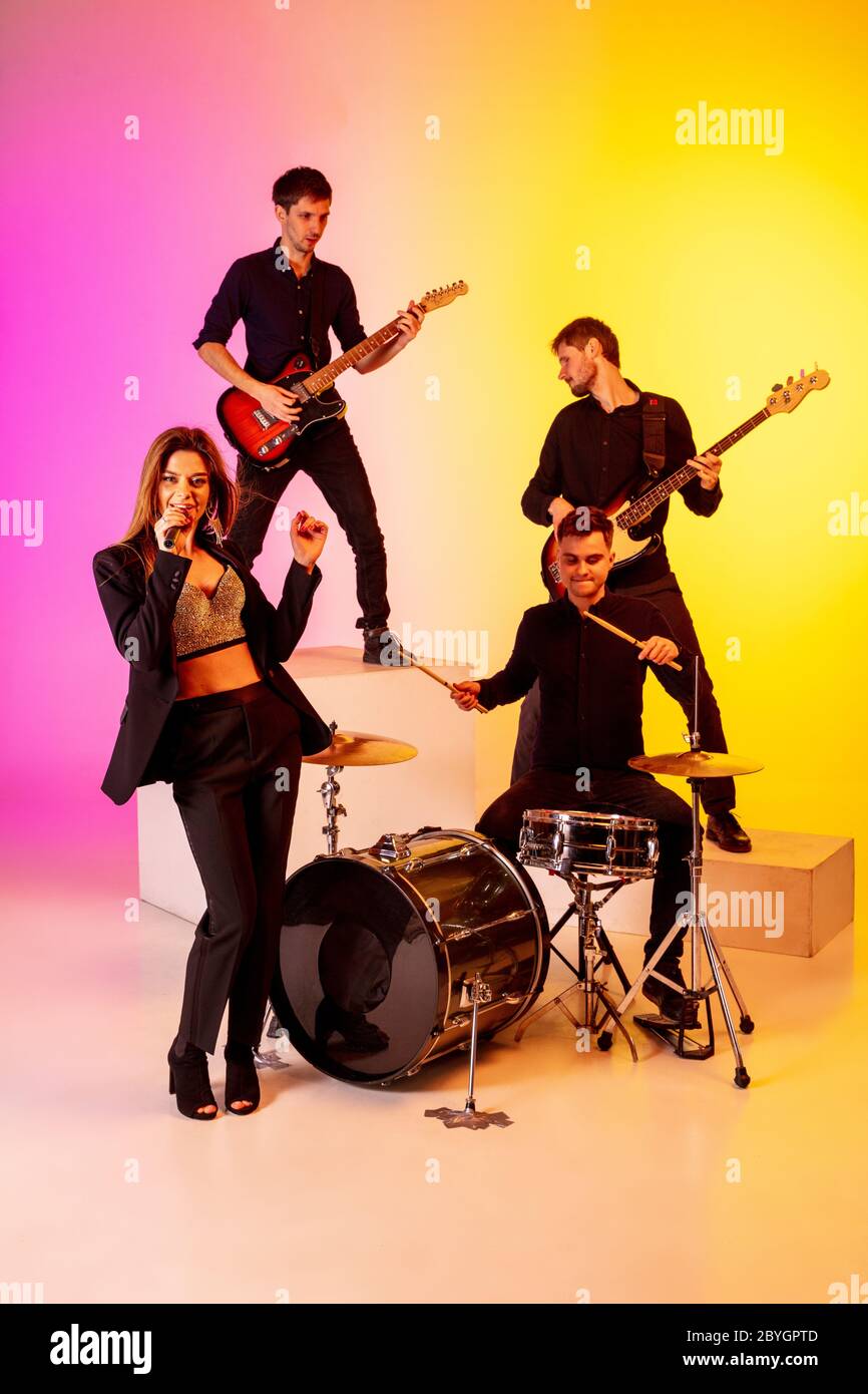 Young and joyful caucasian musicians performing on gradient studio ...