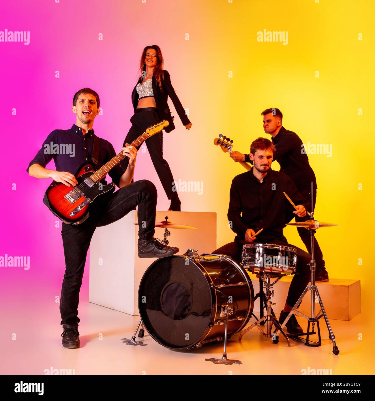 Young and joyful caucasian musicians performing on gradient studio ...