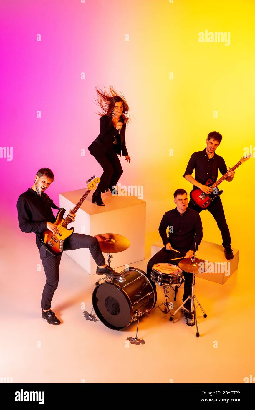 Young and joyful caucasian musicians performing on gradient studio ...