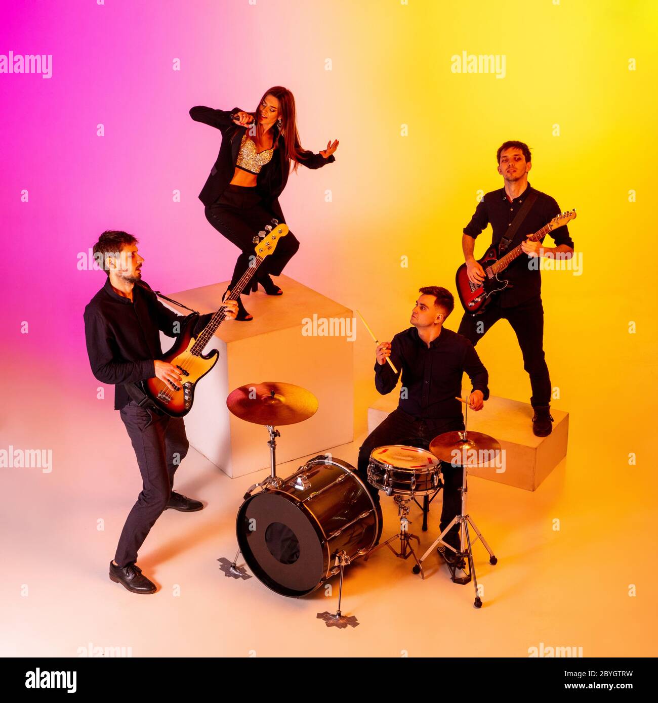 Young and joyful caucasian musicians performing on gradient studio ...