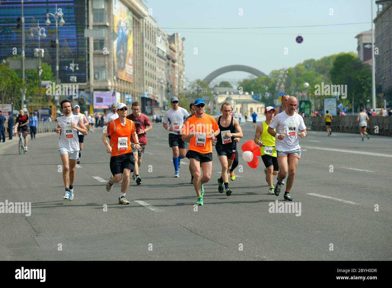 Group of men in tracksuits running down the street. Marathon among ...