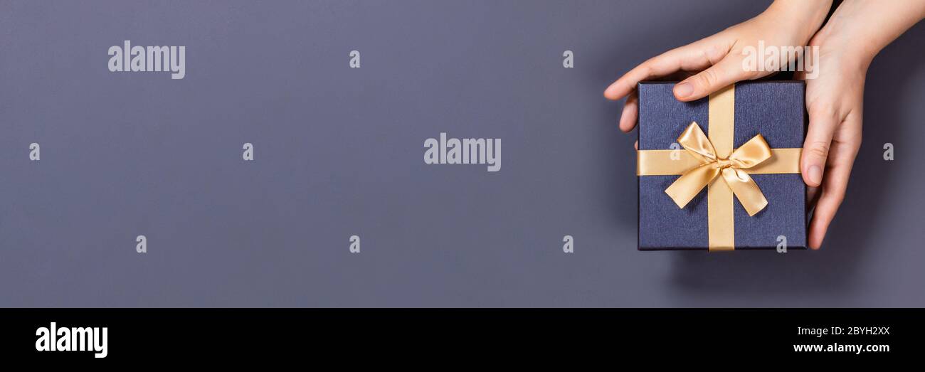 Web banner with women's hands holding a box with a gift or surprise on ...