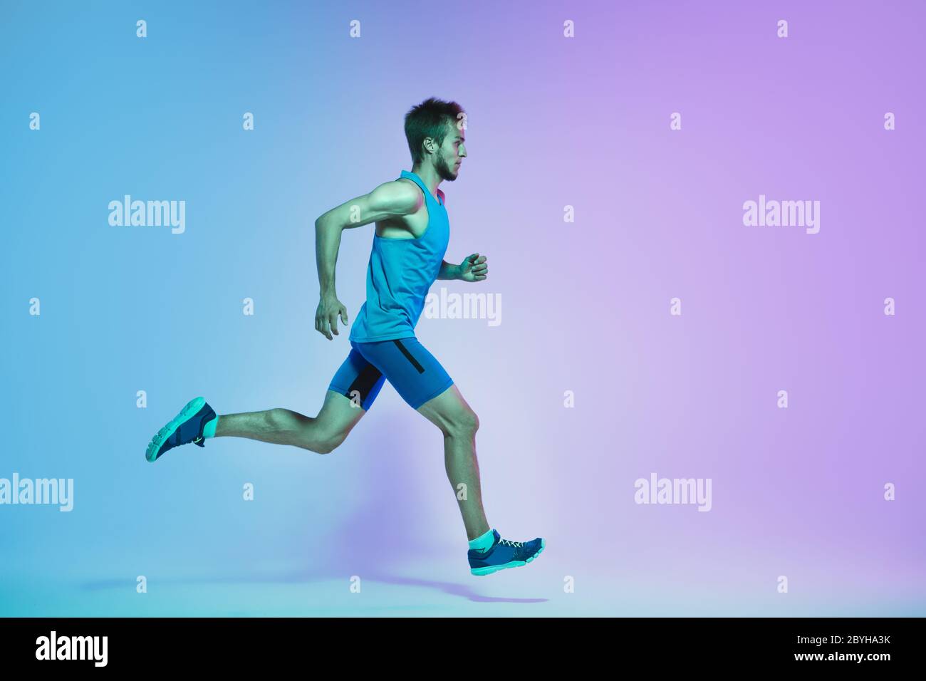 In jump. Portrait of young caucasian man running, jogging on gradient ...