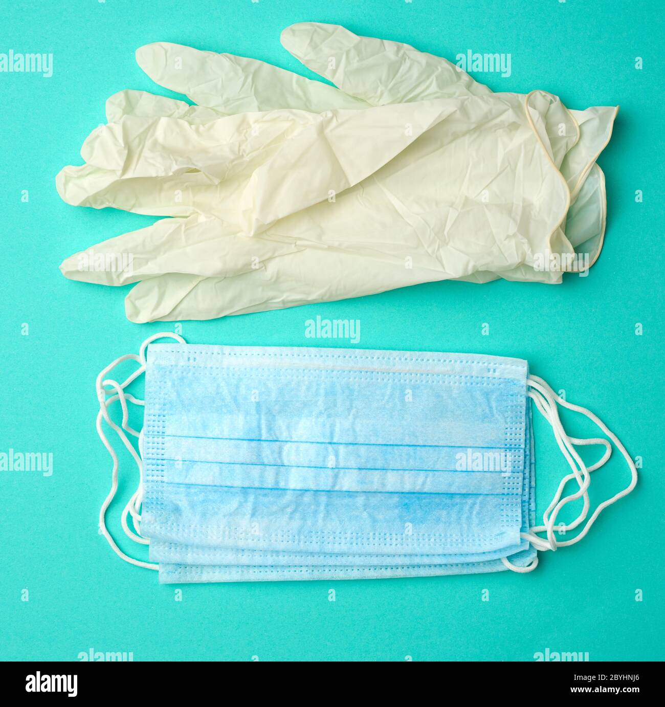 white latex gloves and disposable masks on a green background, hygiene ...