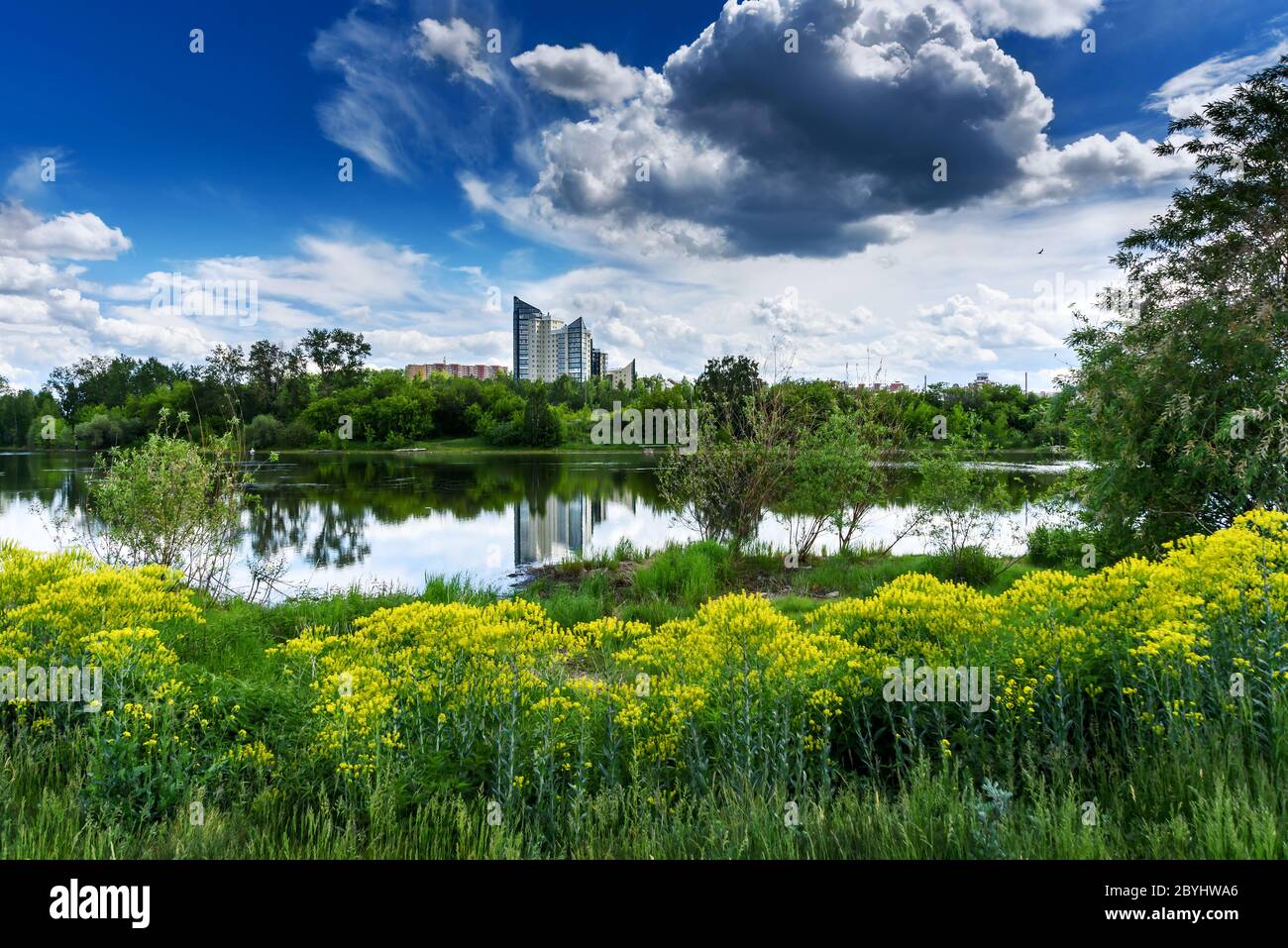 Modern building is reflected in lake in city Park. Summer Sunny day in ...