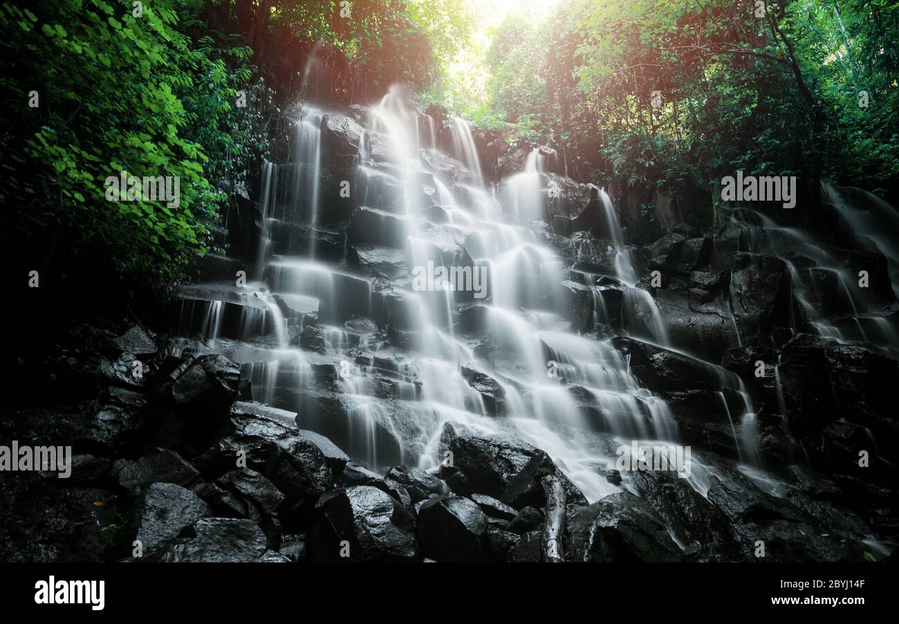 Amazing woman enjoying under stream of big and beautiful cascade ...