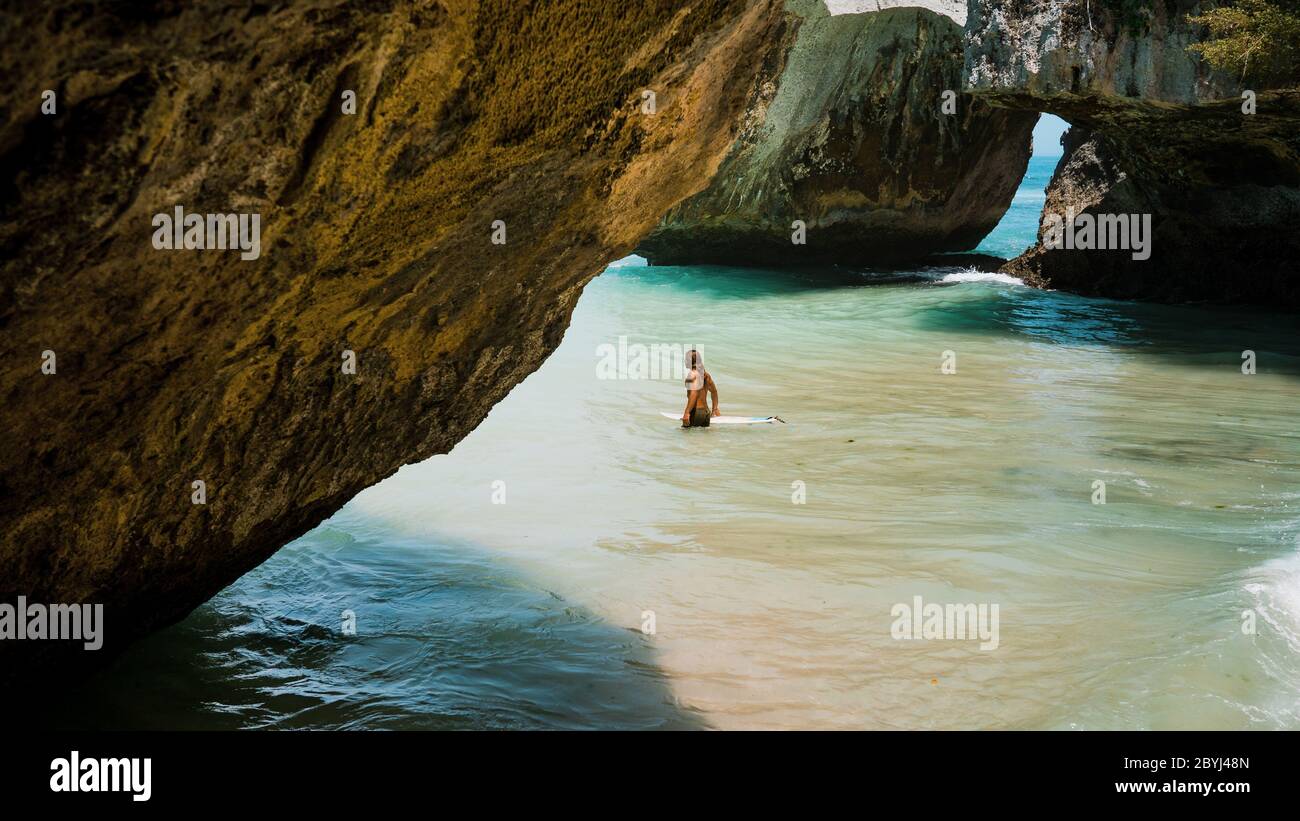 Young surfer sport man carrying his surfing board and going out the ...