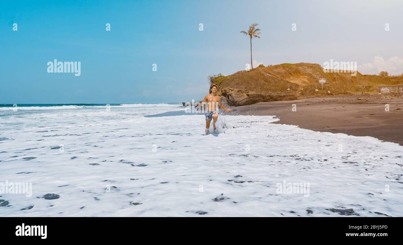Sporty fitness man runner running on sunrise beach. Empty beach in Bali ...