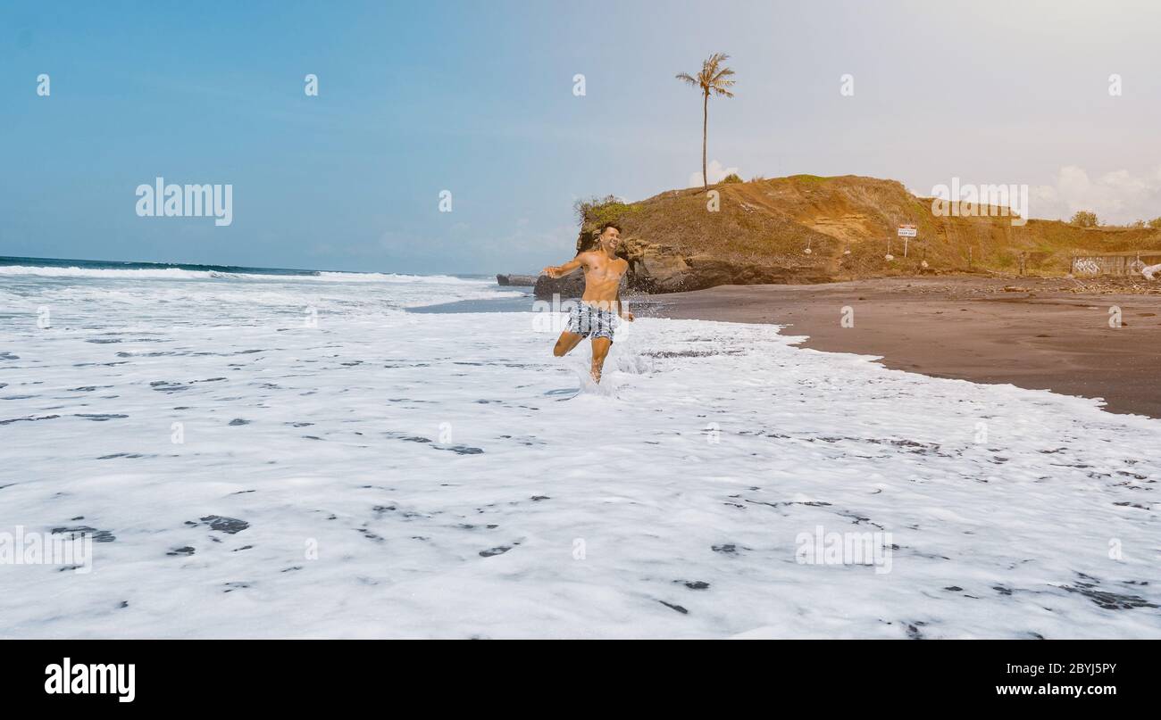 Sporty fitness man runner running on sunrise beach. Empty beach in Bali ...