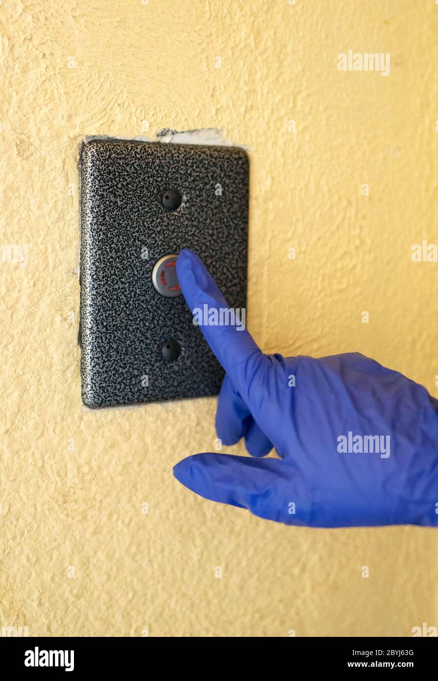 Hand in glove pressing the elevator button Stock Photo - Alamy