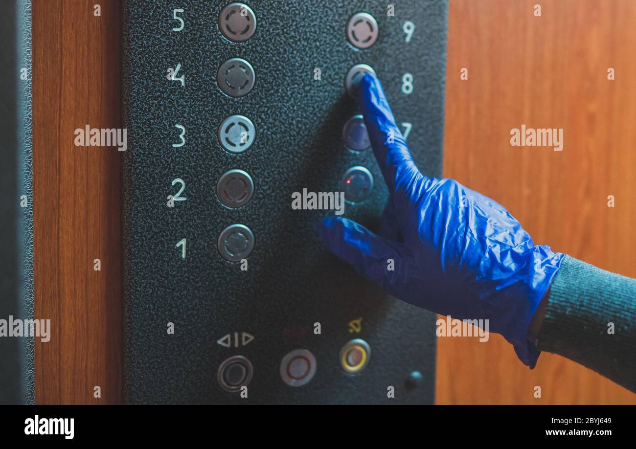 Hand in glove pressing the elevator button Stock Photo - Alamy
