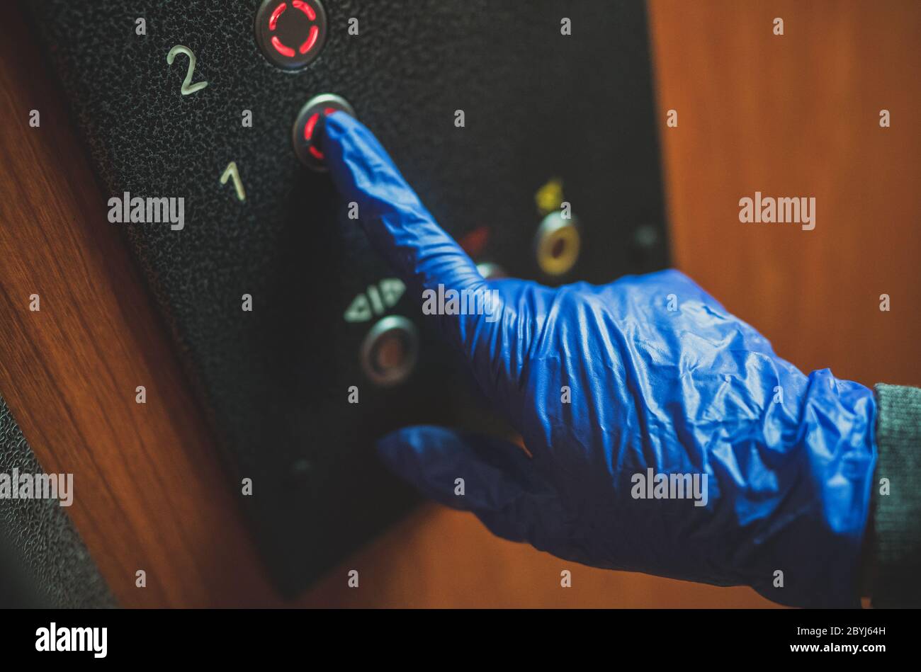 Hand in glove pressing the elevator button Stock Photo - Alamy