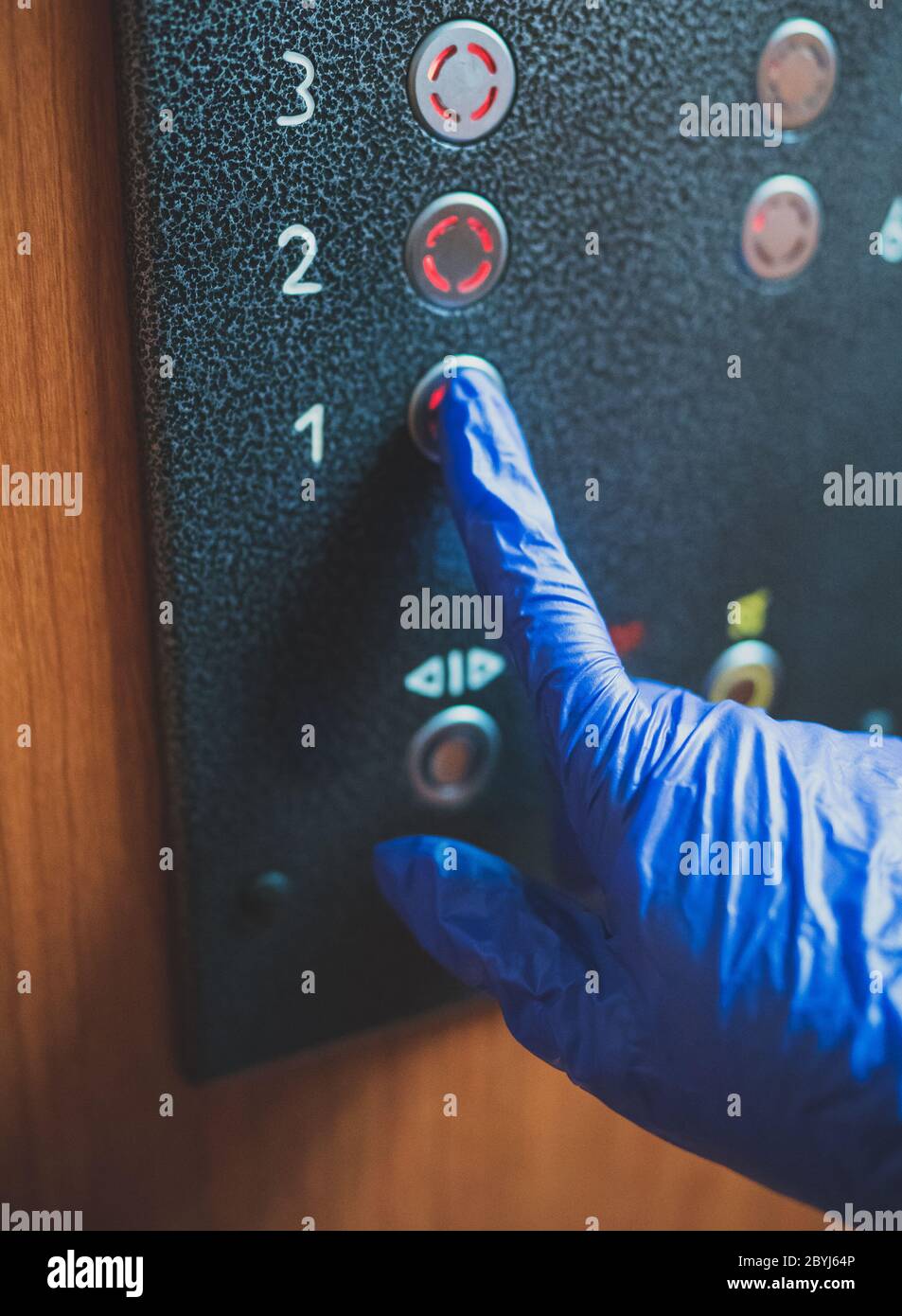 Hand in glove pressing the elevator button Stock Photo - Alamy