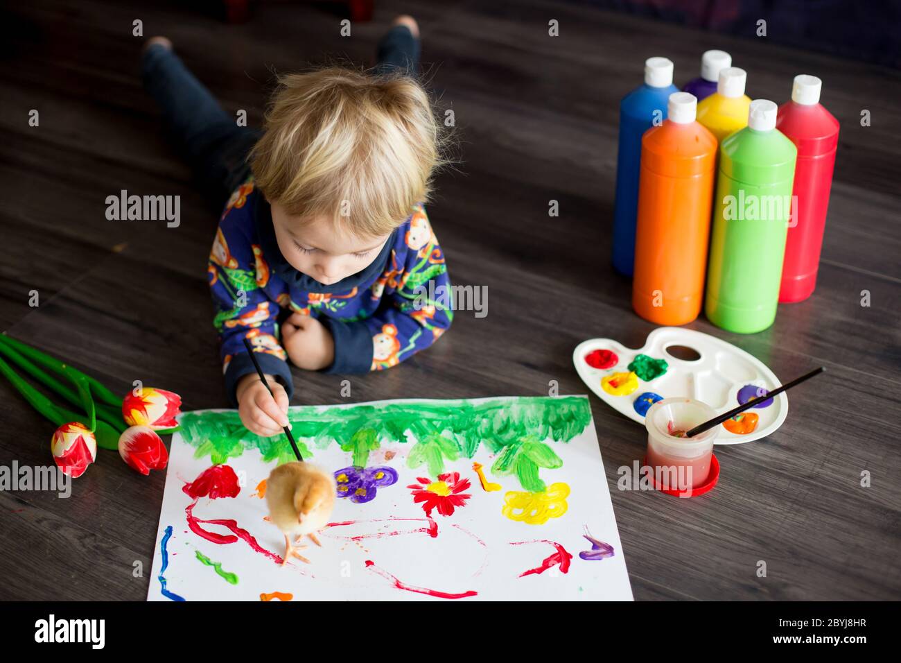 Sweet toddler blond child, boy, painting with colors, little chicks ...