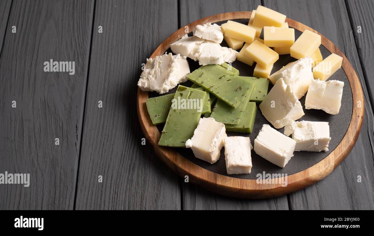 Various types of colorful cheeses diced on plate on wooden table. White ...
