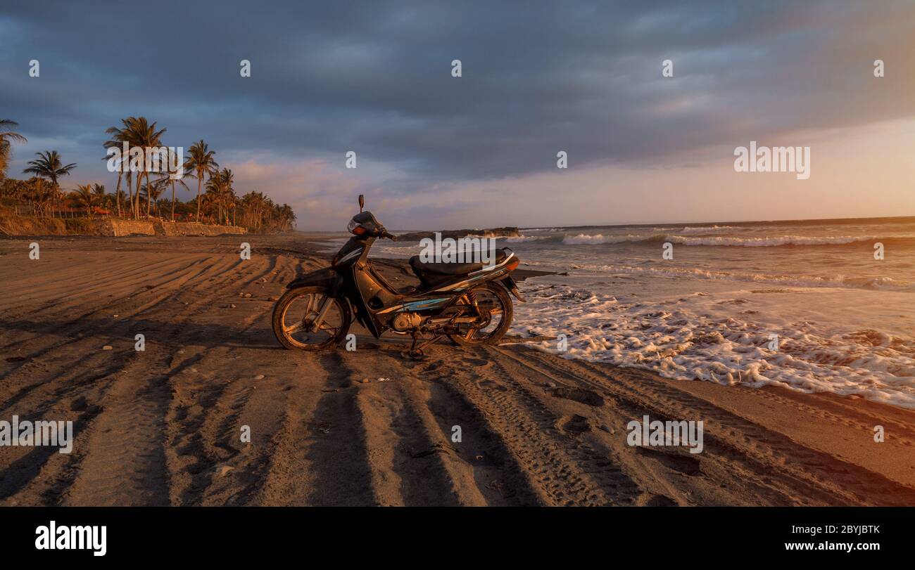 Motorbike on empty sand beach fresh air and breeze at sunset. Having ...