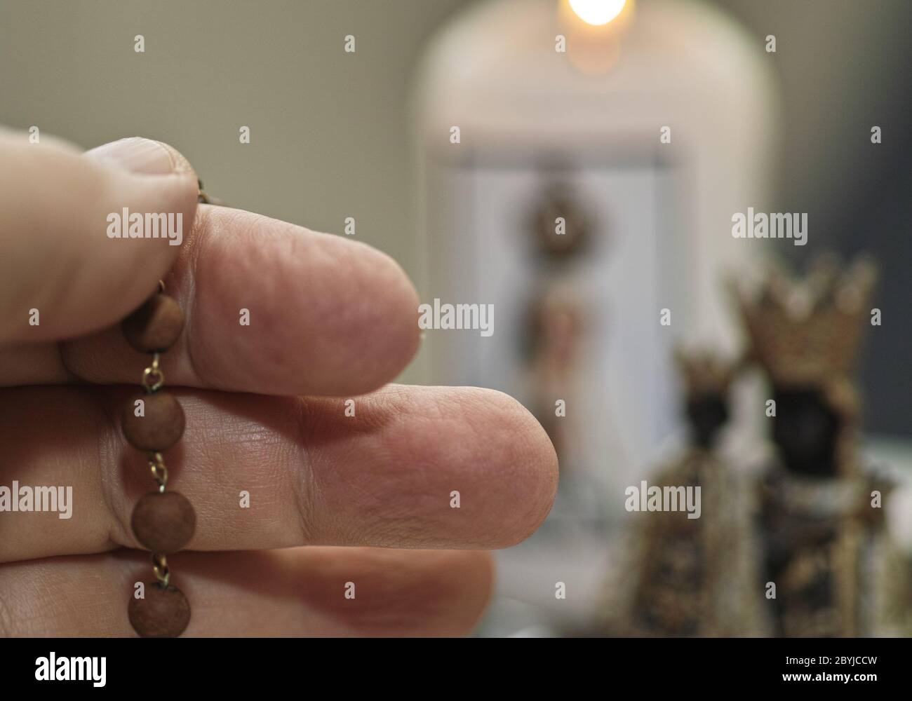 Human hand hold rosario. Saint Mary sculpture and candle light ...