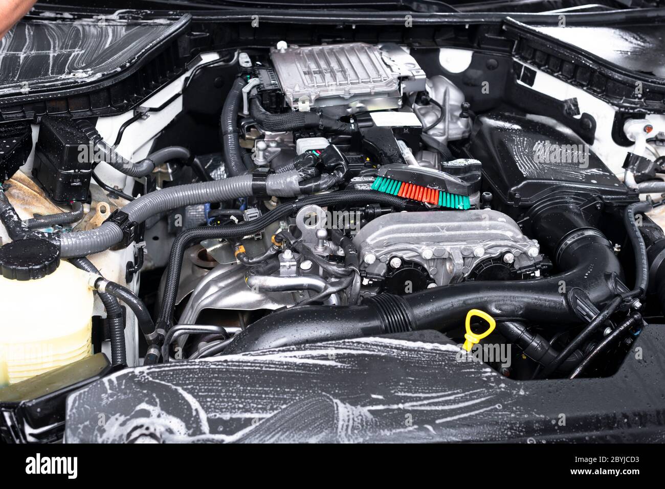 Car detailing maintenance, cleaning engine with the foam and a brush ...